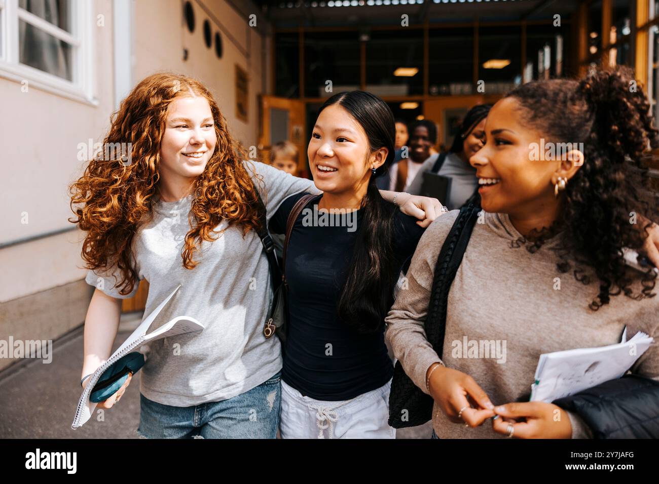 Happy multiracial female students walking on school campus Stock Photo ...