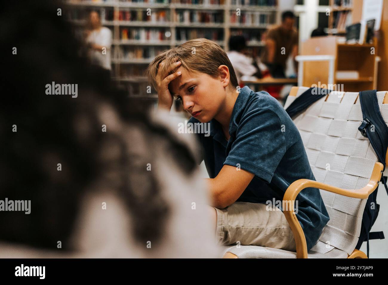 Stressed teenage boy sitting on chair in library at school Stock Photo - Alamy