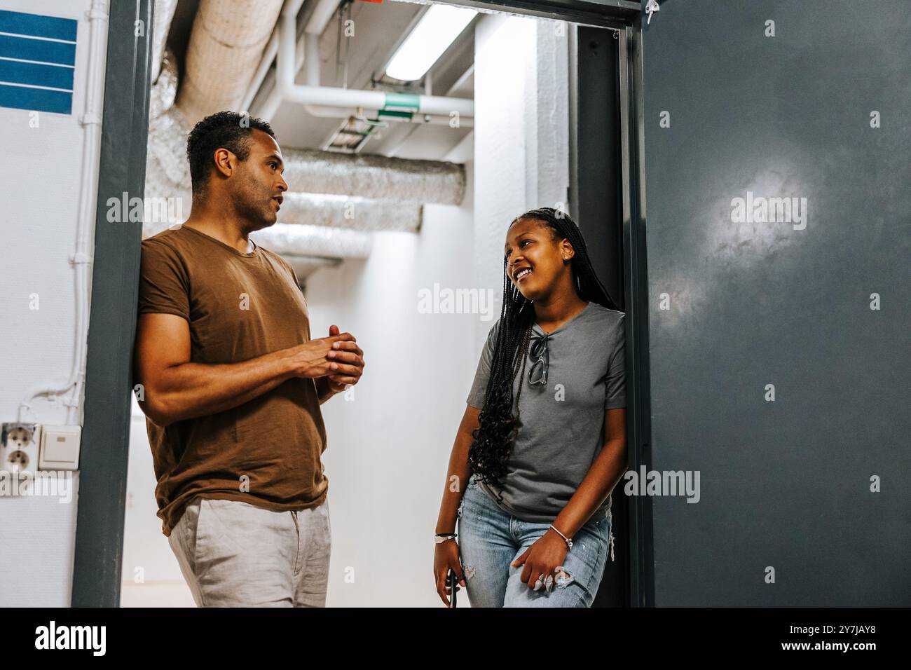 Male professor talking with teenage girl standing near doorway of ...