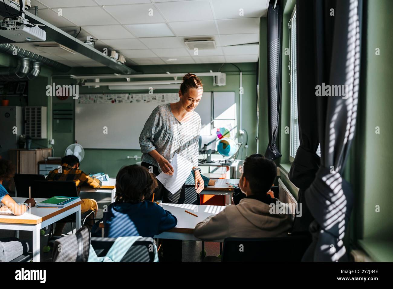Female teacher assisting student sitting in classroom at school Stock ...