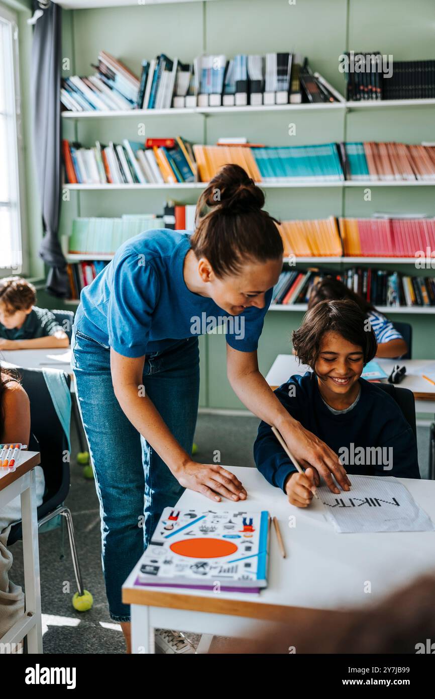 Female professor helping elementary student with creativity in drawing ...