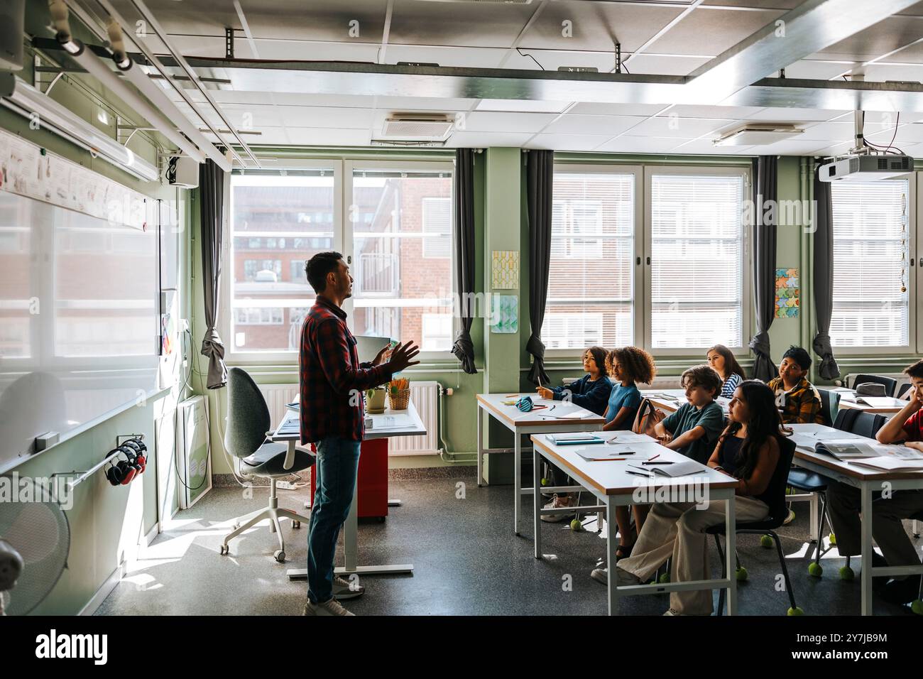 Side view of male professor teaching group of students in classroom at ...