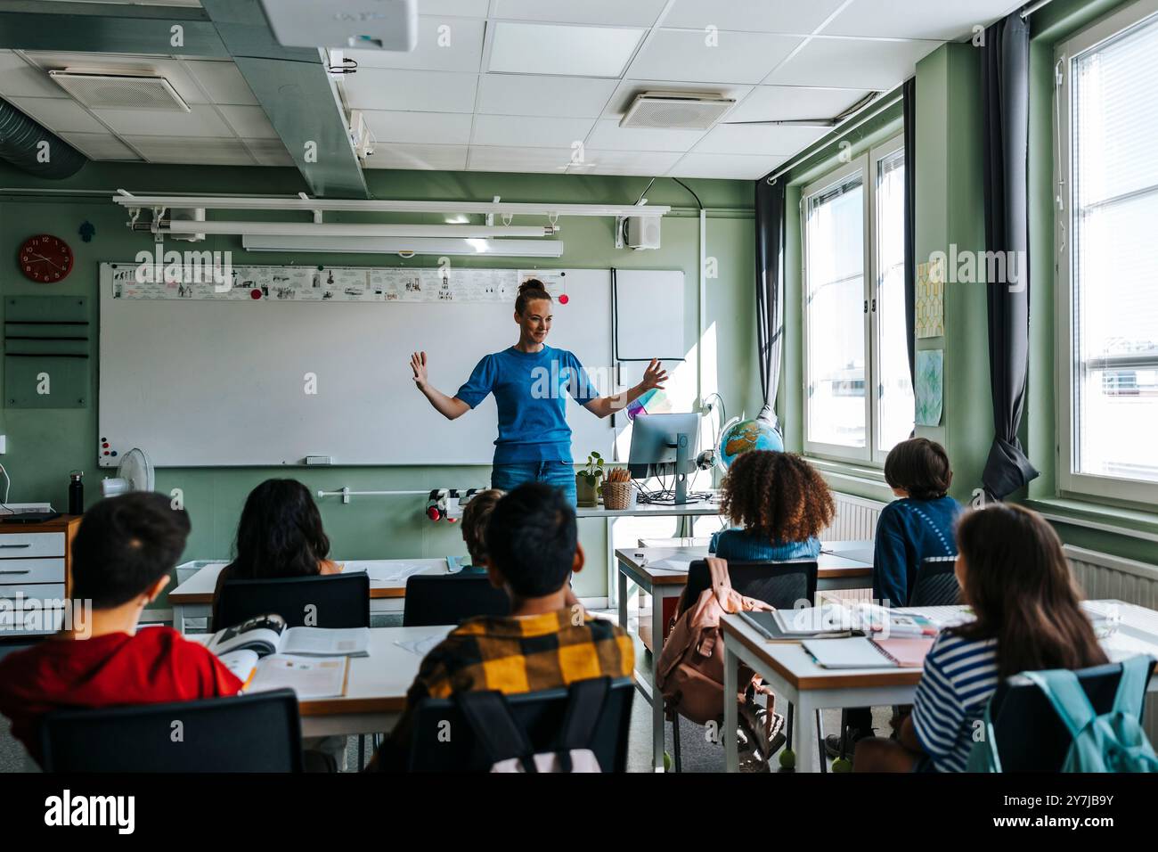 Female professor with arms outstretched teaching group of students in ...