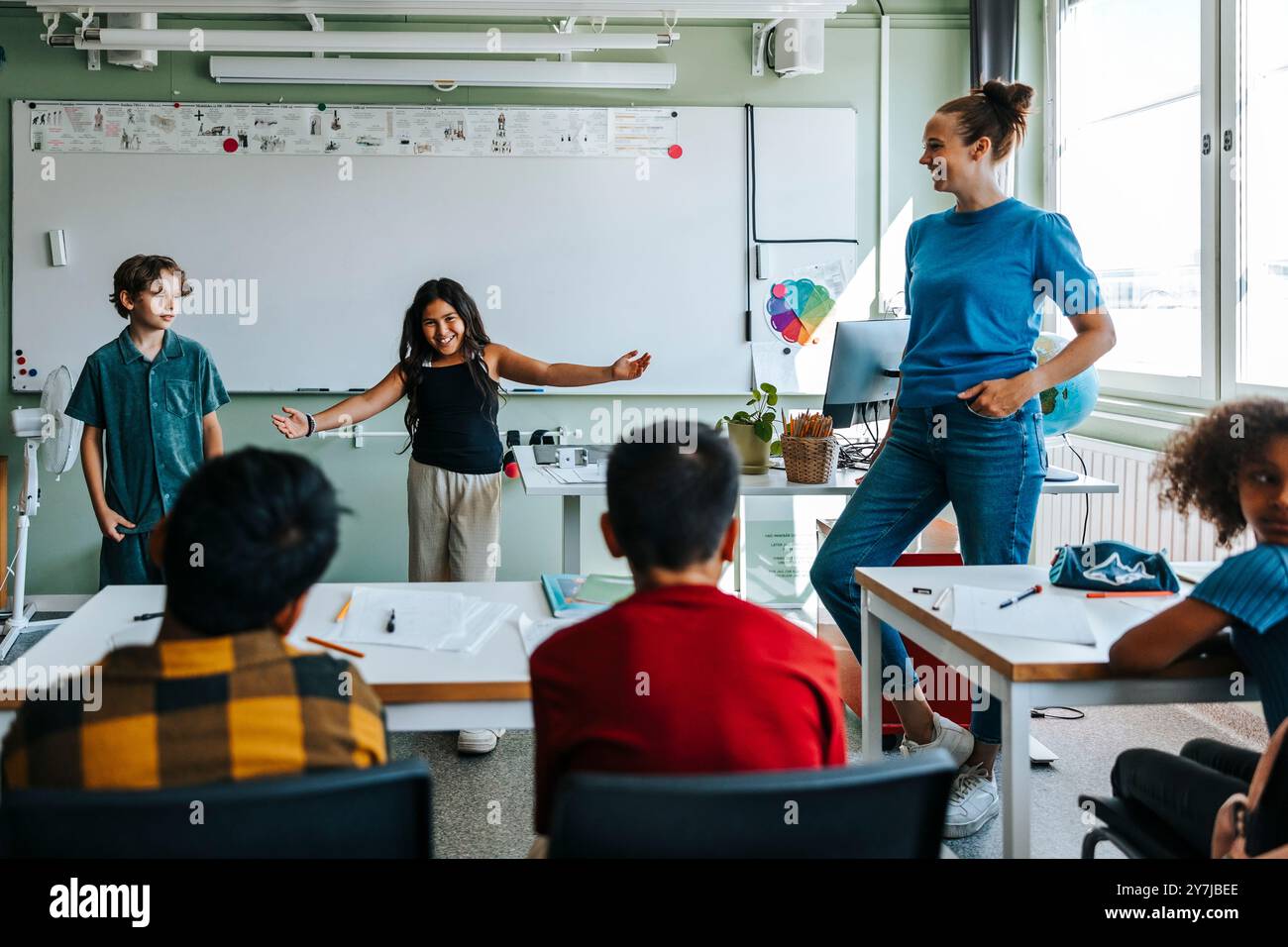 Happy girl standing with arms outstretched in front of whiteboard in ...