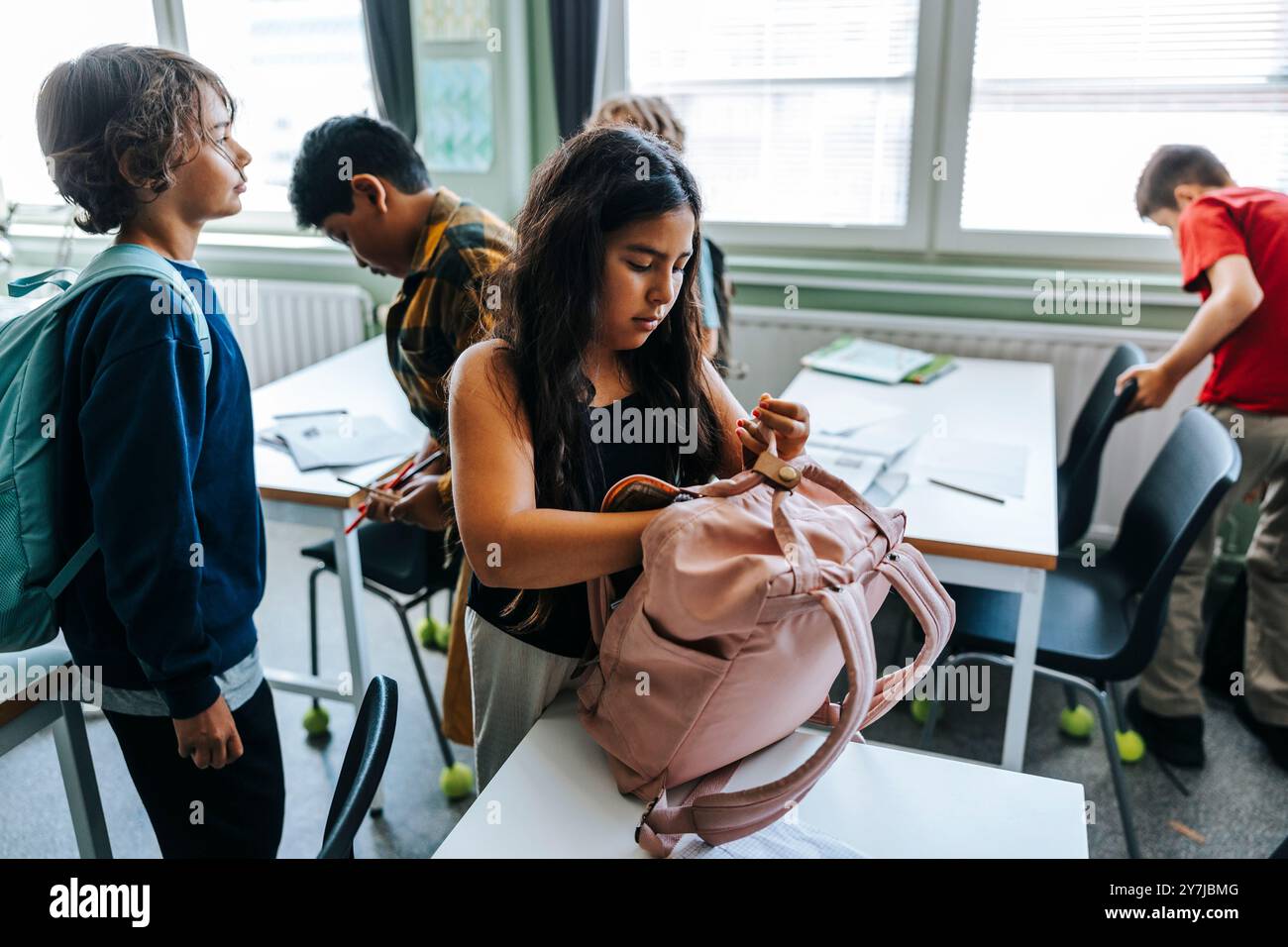 Schoolgirl packing bag while standing in classroom Stock Photo - Alamy