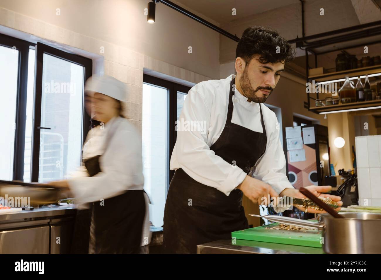 Male chef wearing apron and preparing food at commercial kitchen in ...