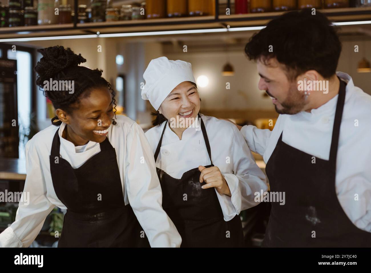 Male chef enjoying with female colleagues at commercial kitchen in ...