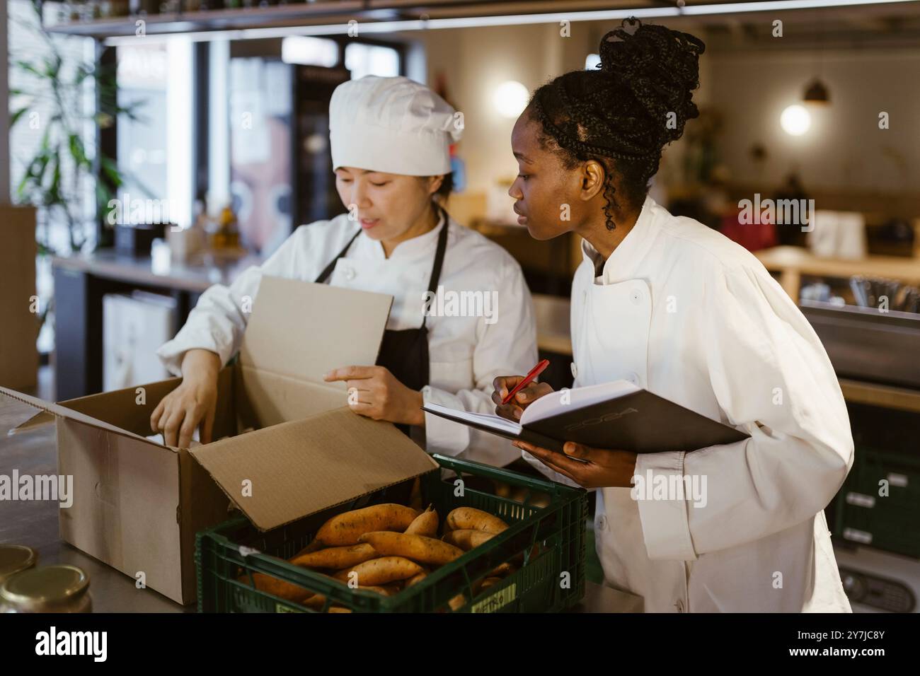 Young chef bookkeeping while taking inventory with female colleague in ...