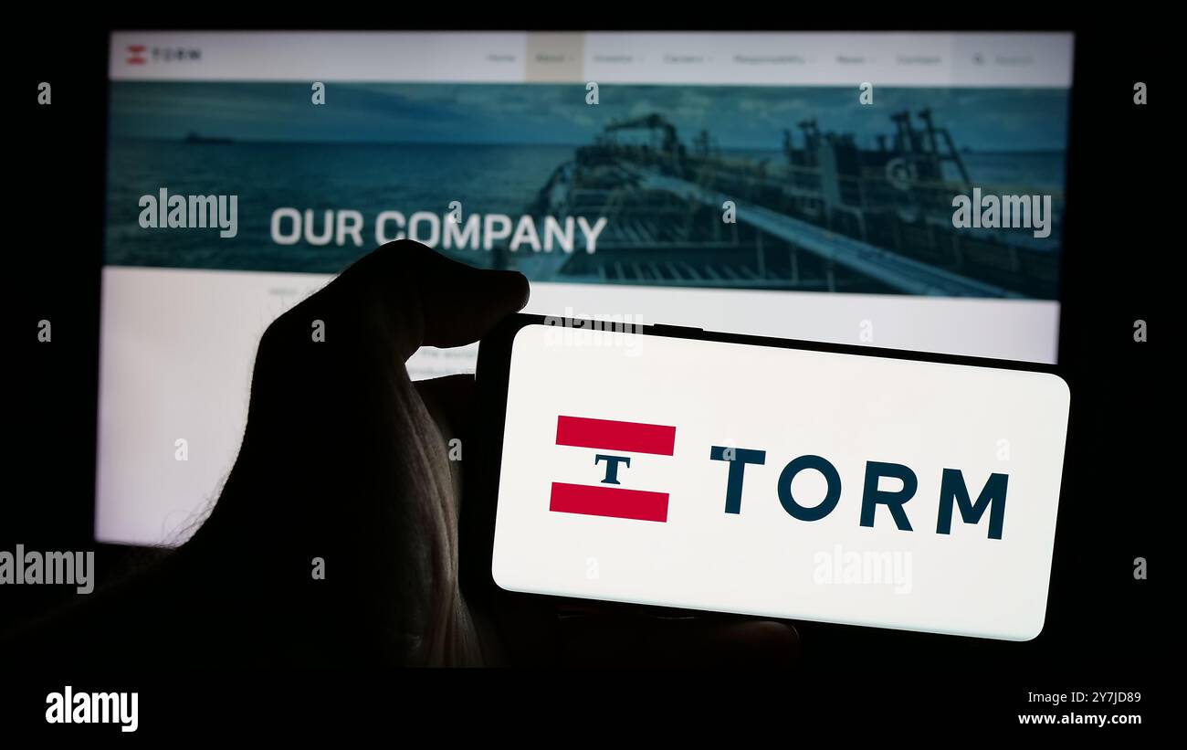 Person holding smartphone with logo of Danish shipping company TORM plc ...
