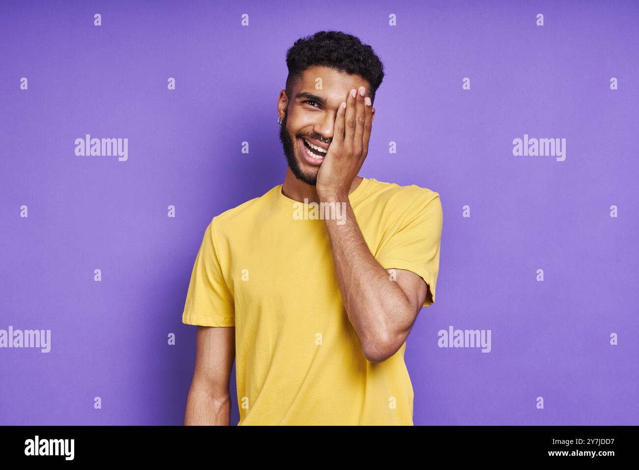 Happy African man covering half face with hand smiling while standing ...