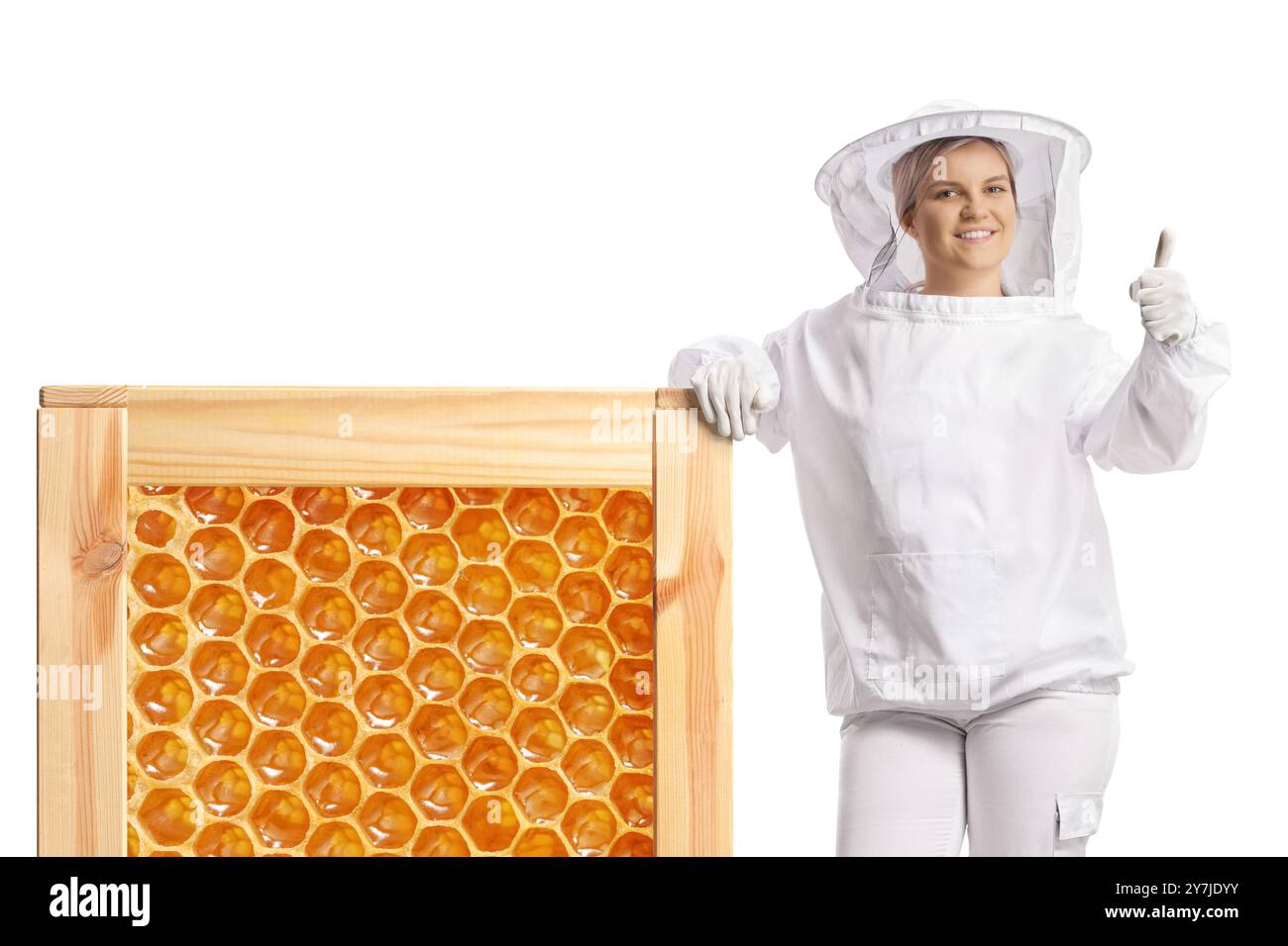 Young female bee keeper in a uniform leaning on a honeycomb frame and ...