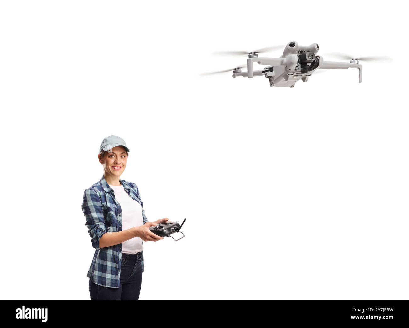 Young female flying a drone and smiling isolated on white background ...