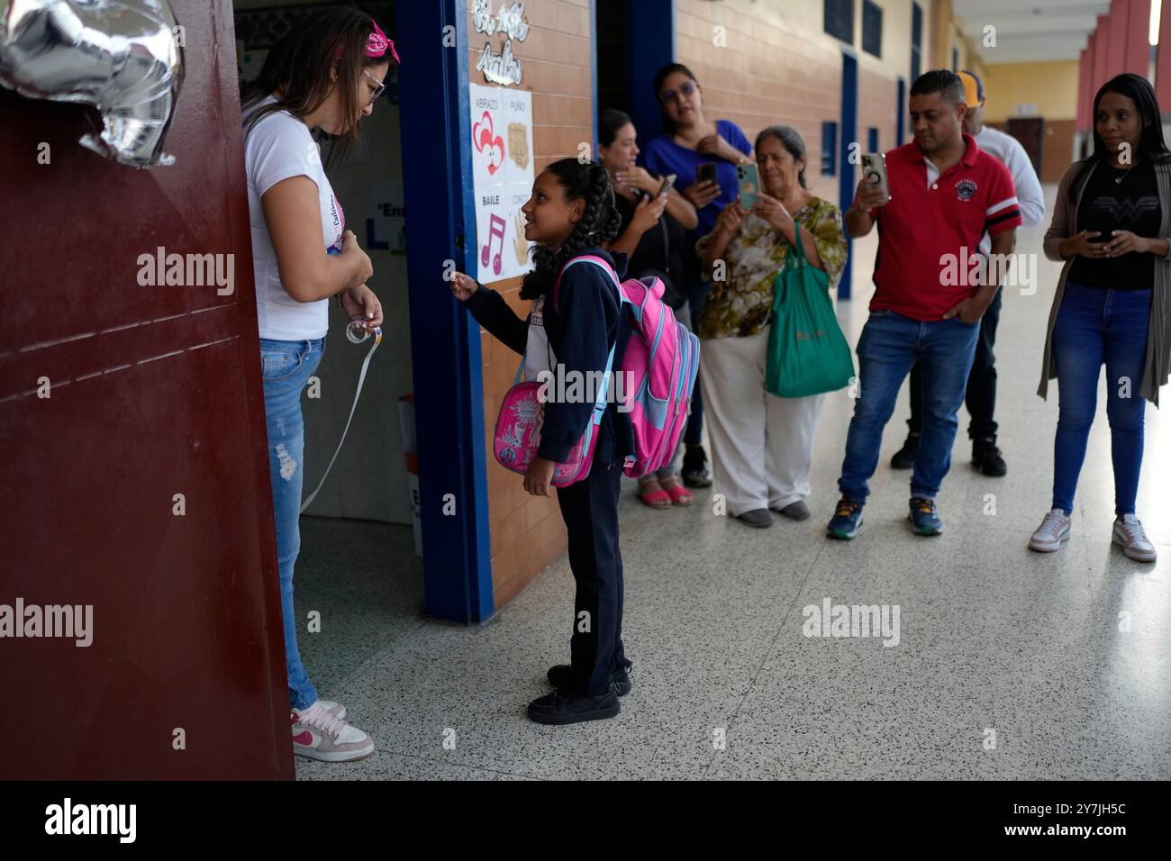A student is welcomed by her teacher on a first day back to school in ...
