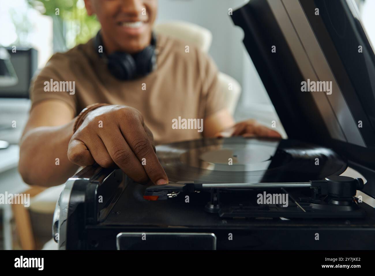 Close-up of happy multiracial man putting vinyl record on turntable ...