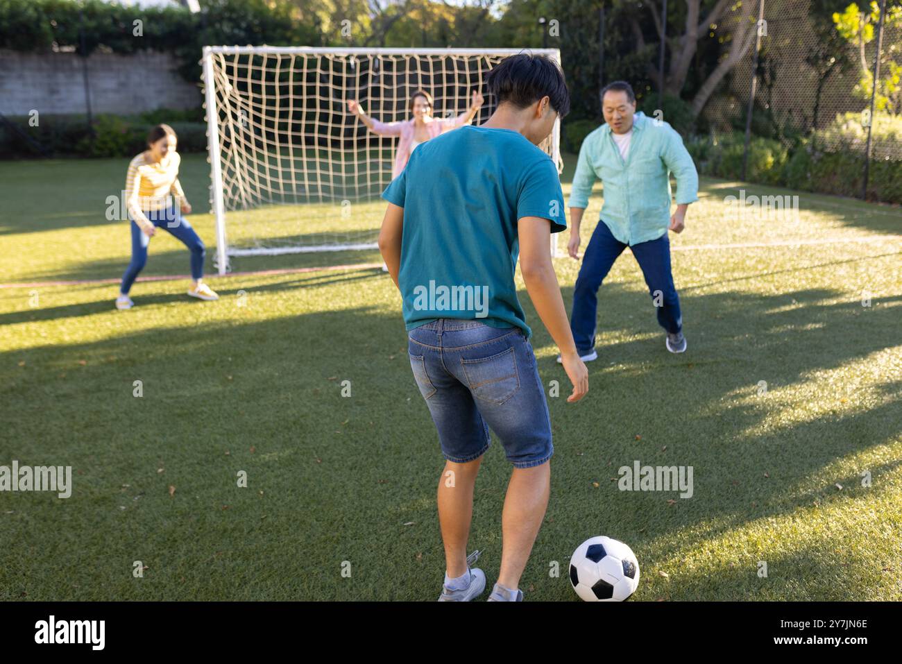 Playing soccer, family enjoying outdoor activity together on grassy ...