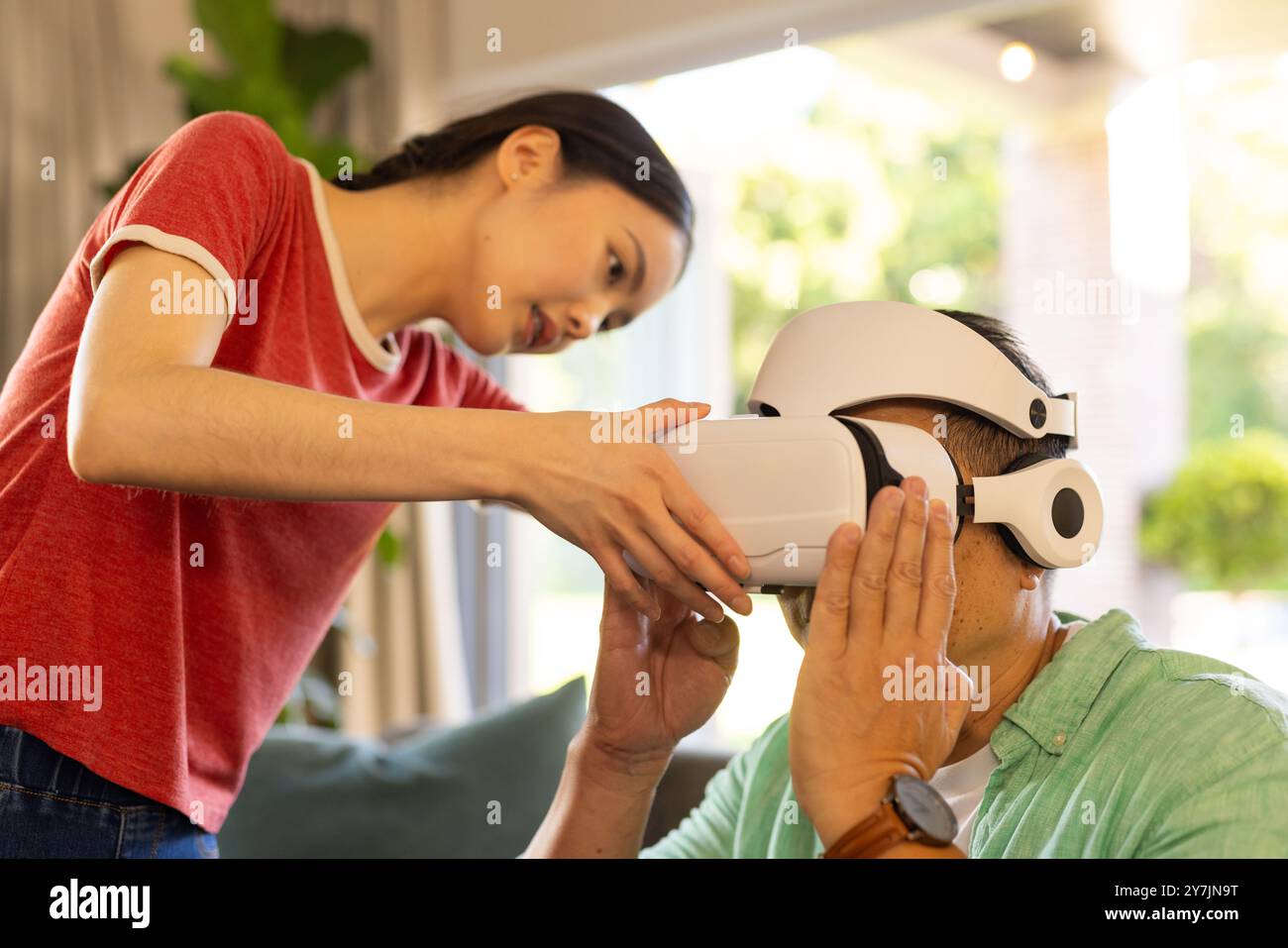 Helping father adjust VR headset, daughter ensuring proper fit and ...