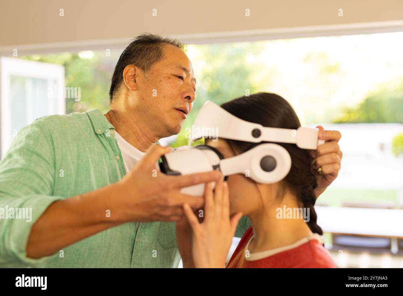 Adjusting VR headset, father helping girl experience virtual reality at ...
