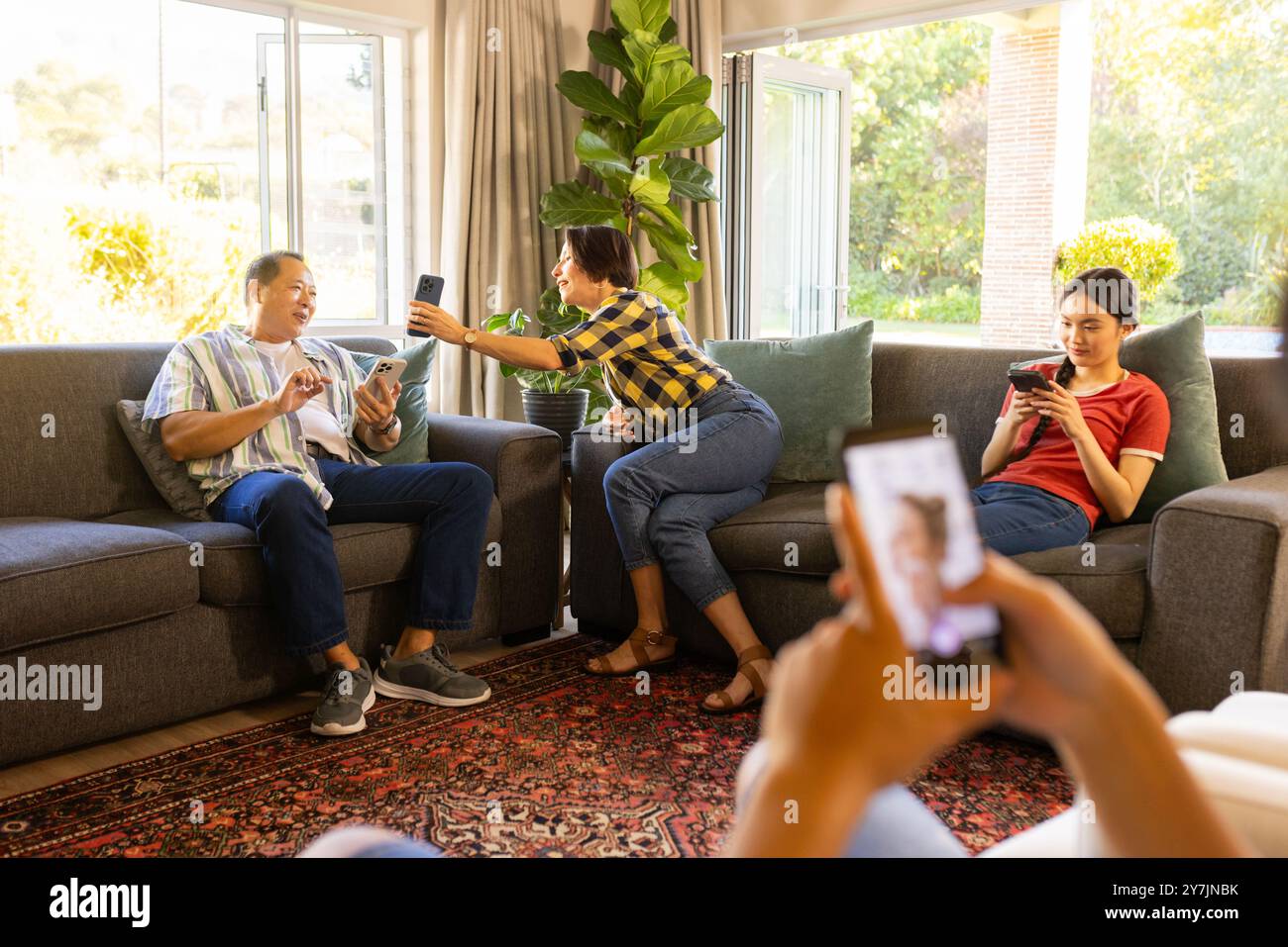 Using smartphones, family members relaxing and interacting in living ...