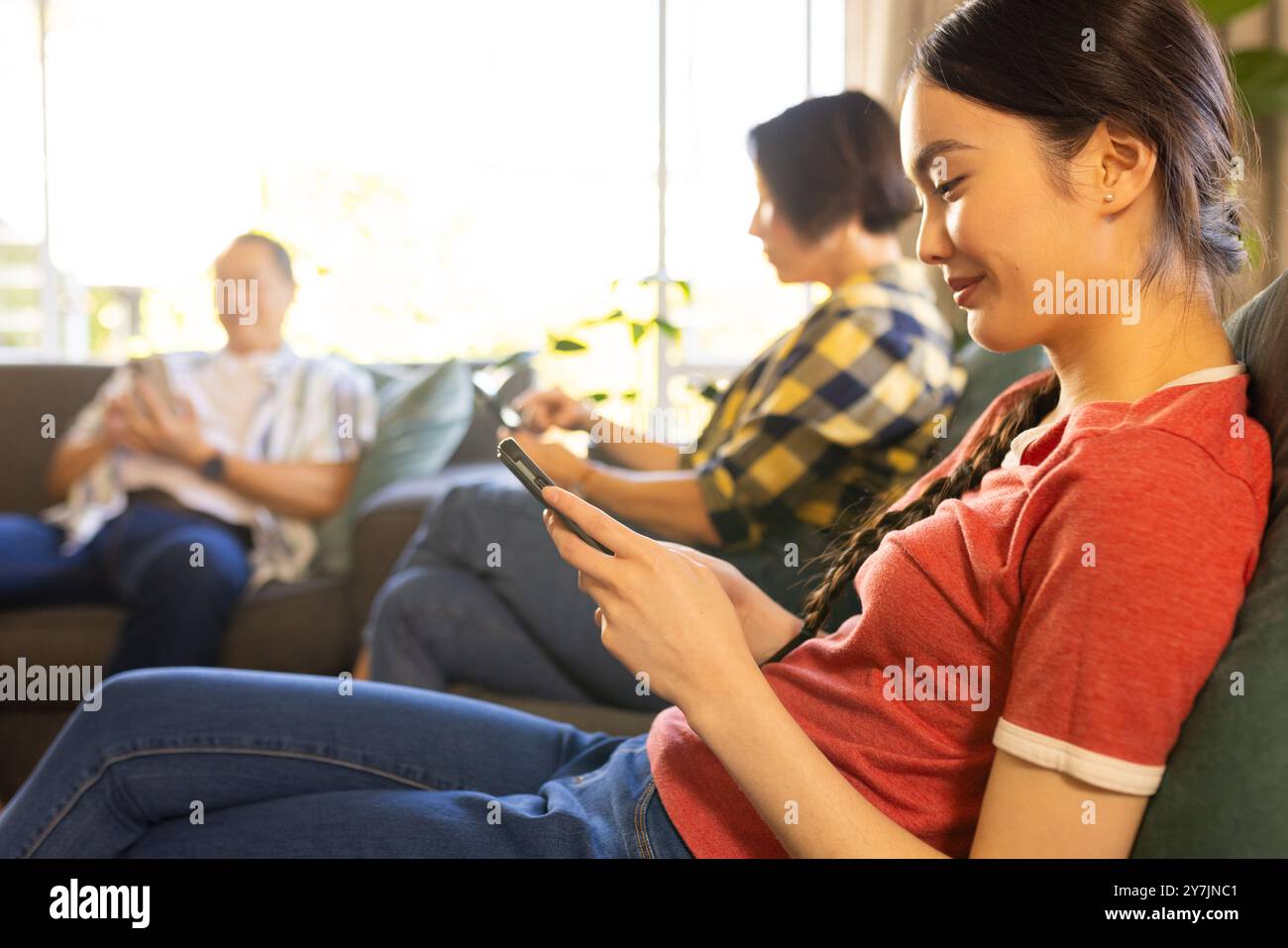 Using smartphones, family members relaxing on couch in living room ...
