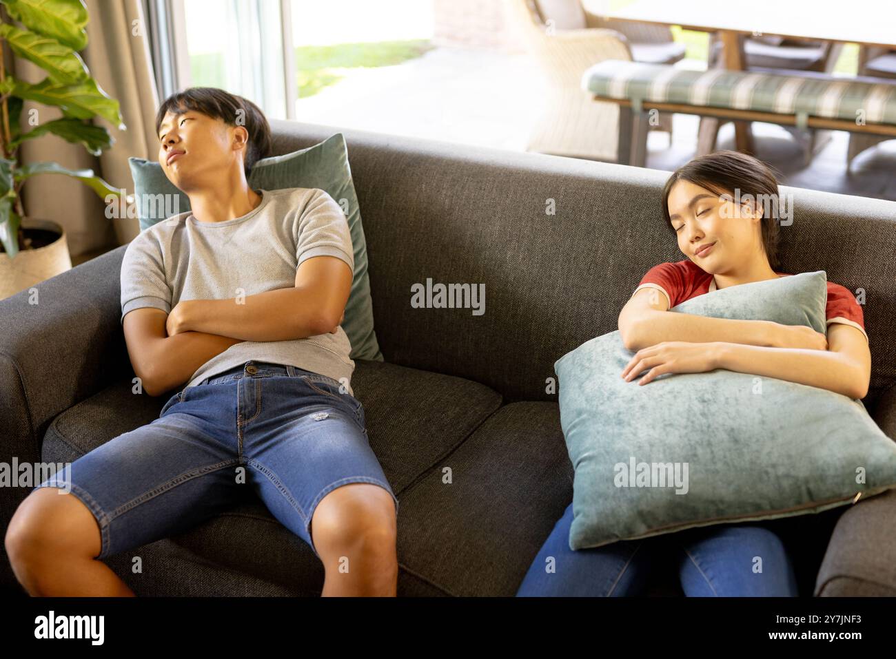 Resting on couch, young siblings napping with pillows in living room ...