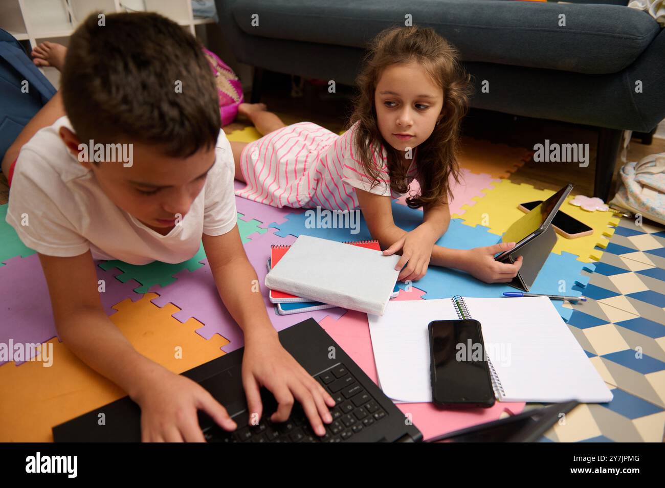 Two children engage in online learning at home using a laptop and ...