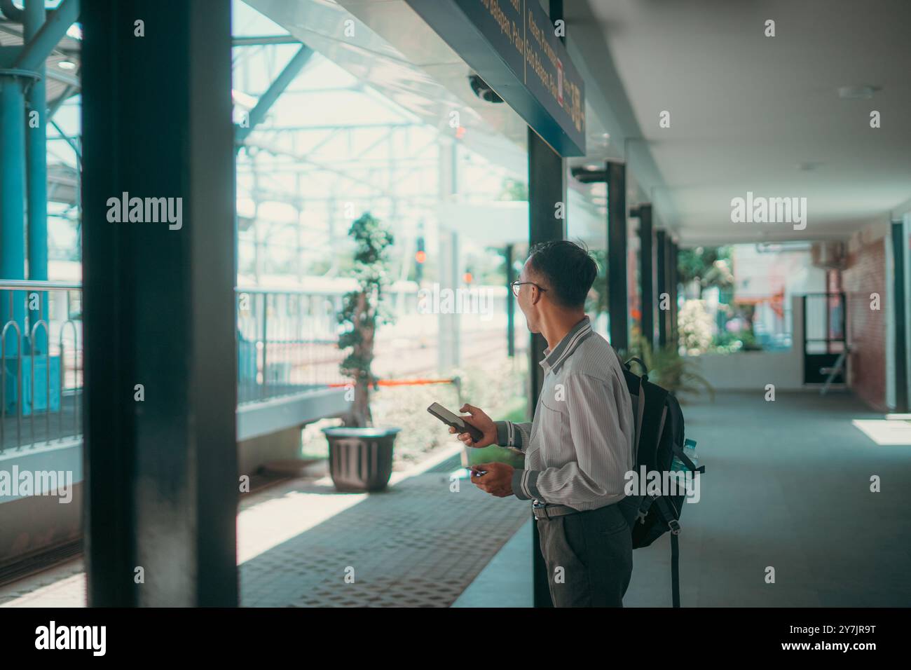 A Young Man is Waiting at a Modern Transit Station, Observing the ...