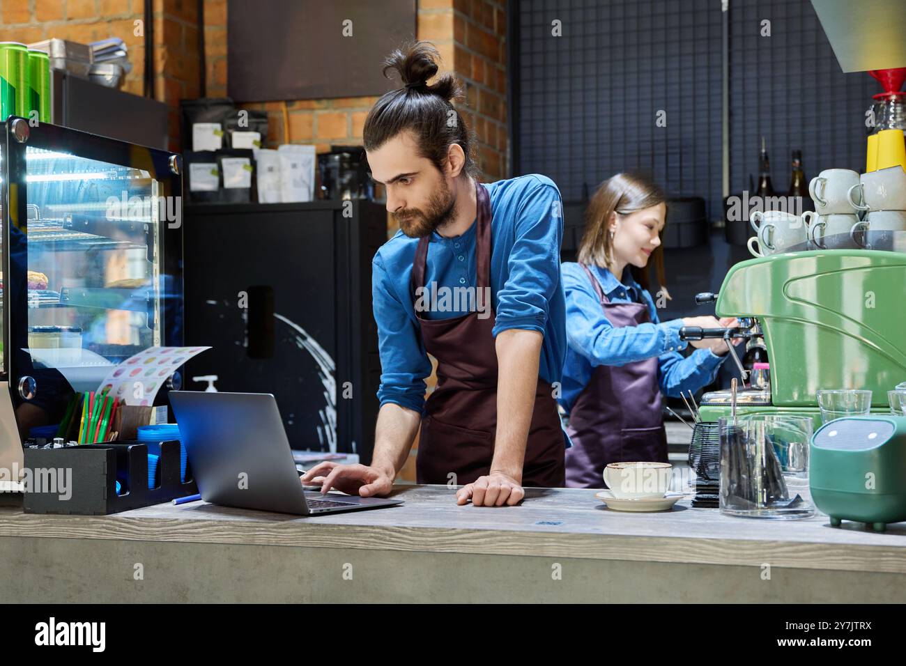 Two cafe workers working together behind counter, at coffee shop Stock ...