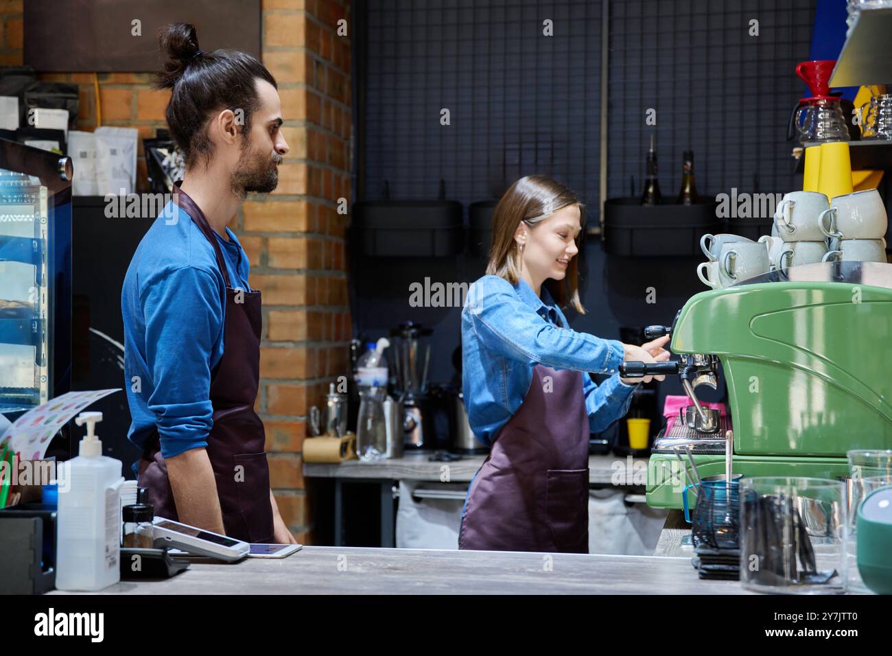 Two cafe workers working together behind counter, at coffee shop Stock ...
