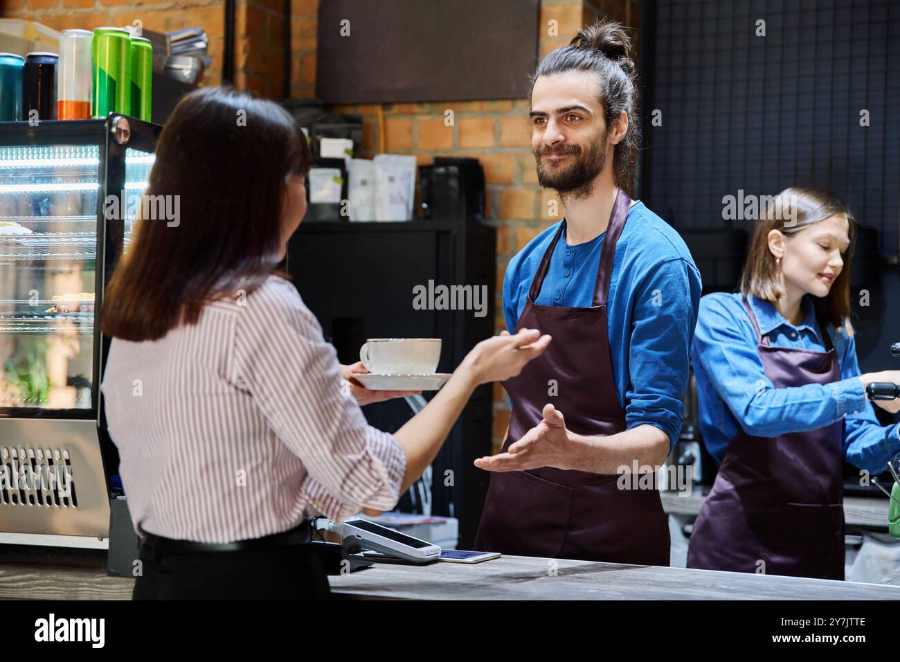 Guy working in cafe with cup of coffee at bar counter serving female ...