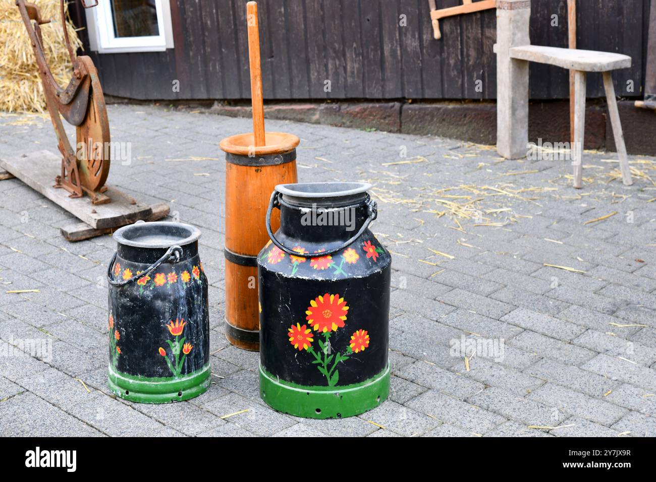 painted milk cans in front of an old butter chum Stock Photo - Alamy