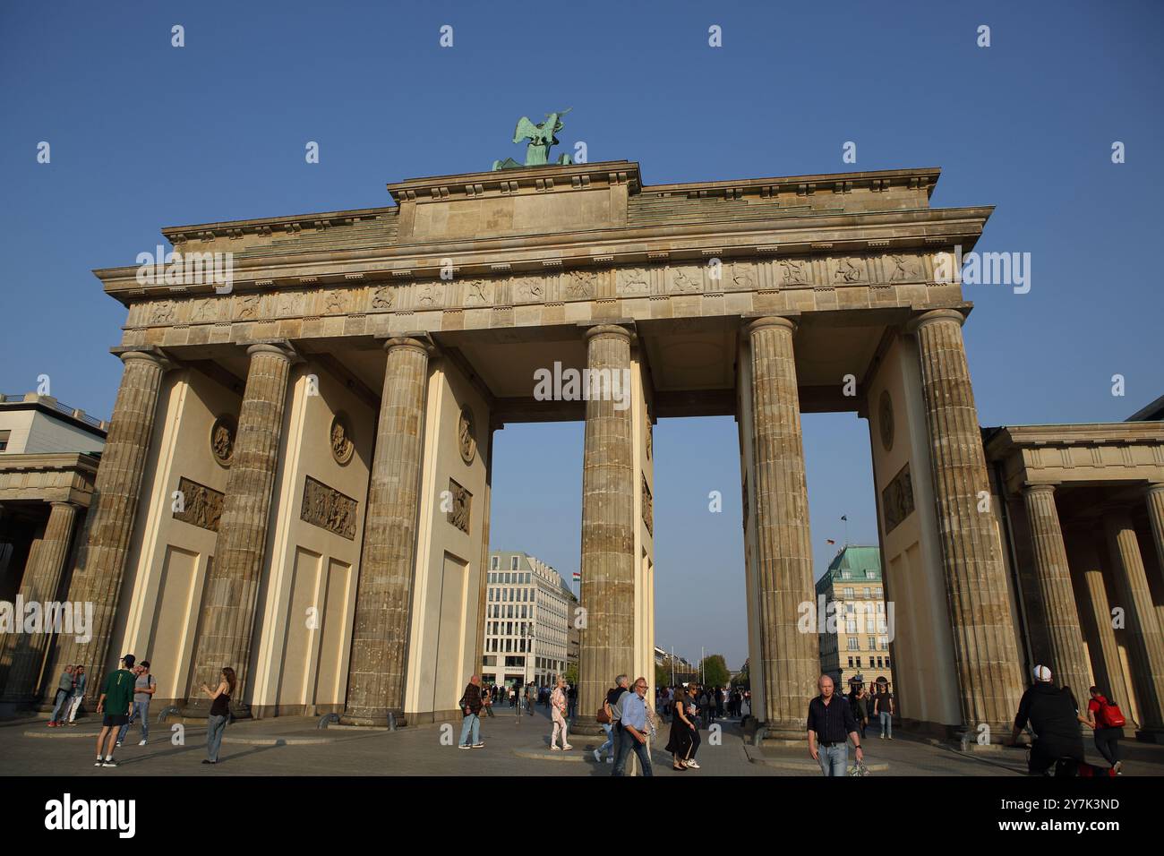 Tourists walk by the back of the Brandenburg Gate with a bronze ...