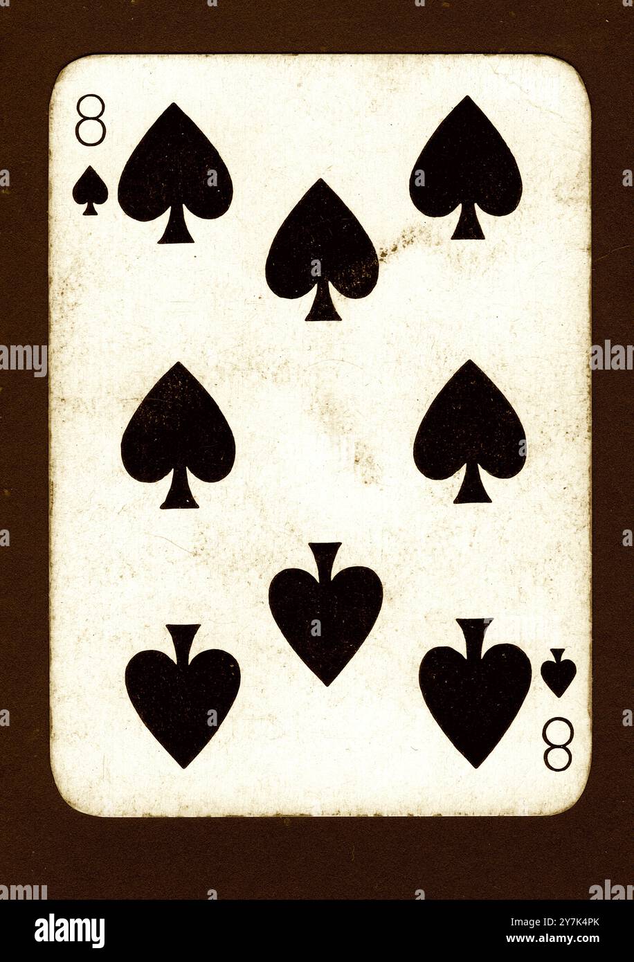 A vintage eight of spades playing card in sepia on a black background ...