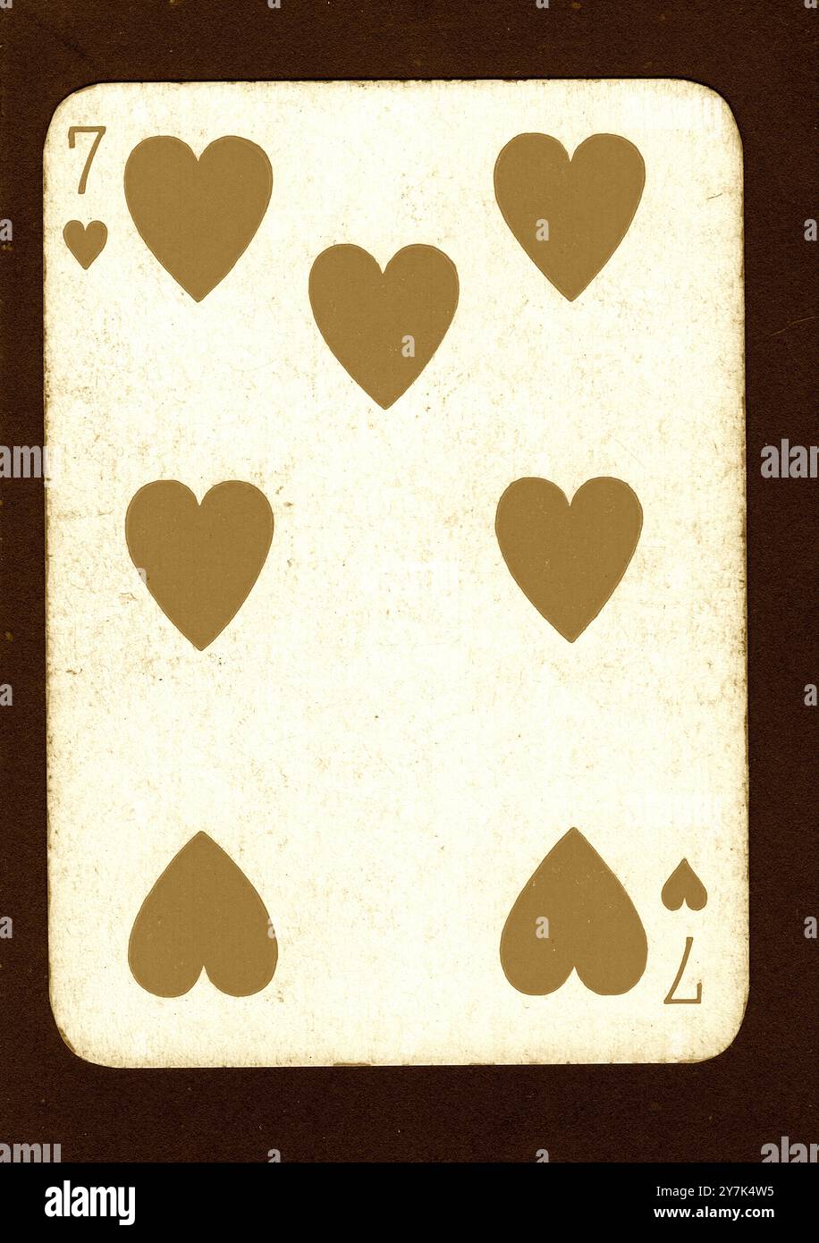 A vintage seven of hearts playing card in sepia on a black background ...
