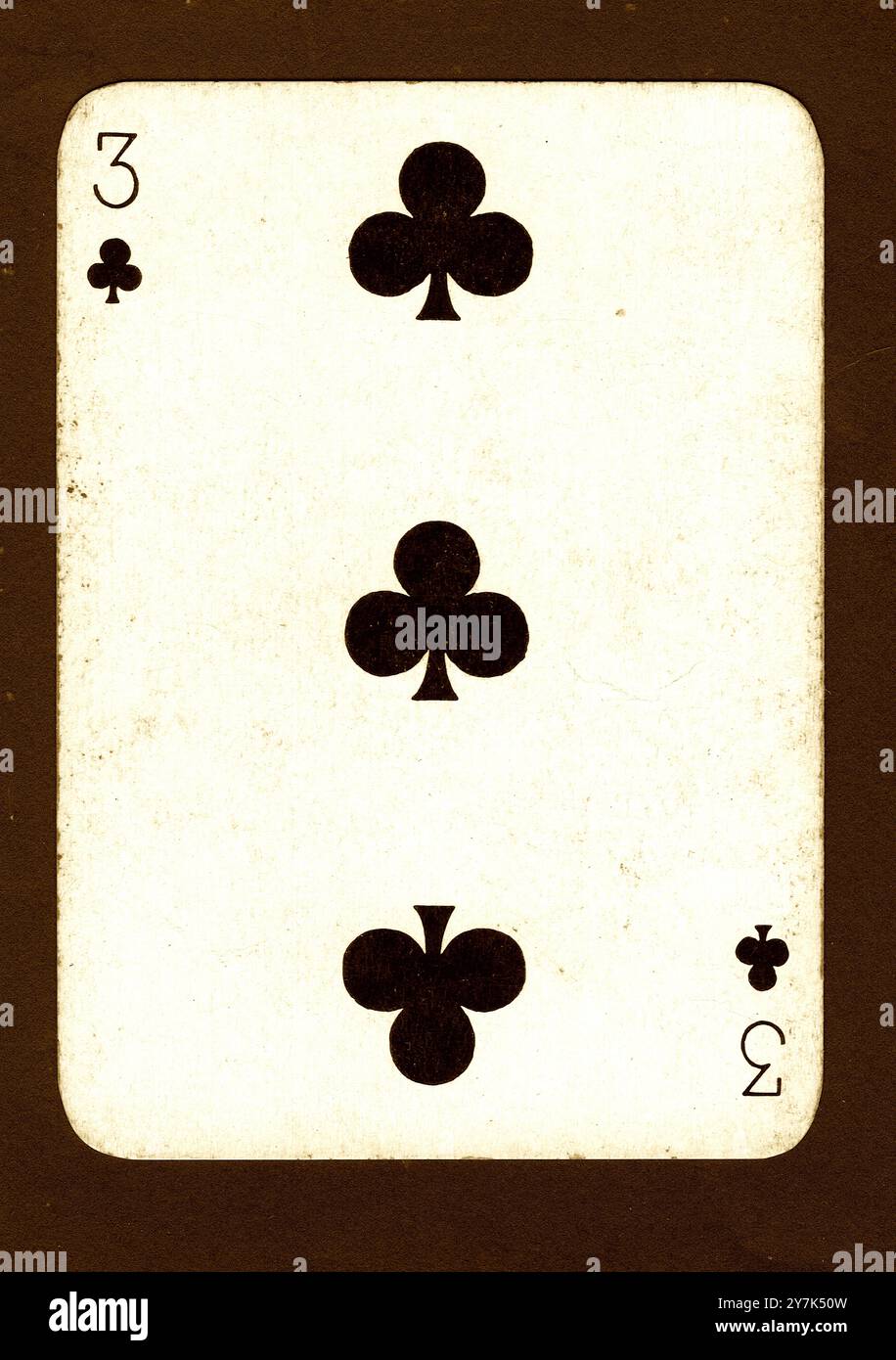 A vintage three of clubs playing card in sepia on a black background ...
