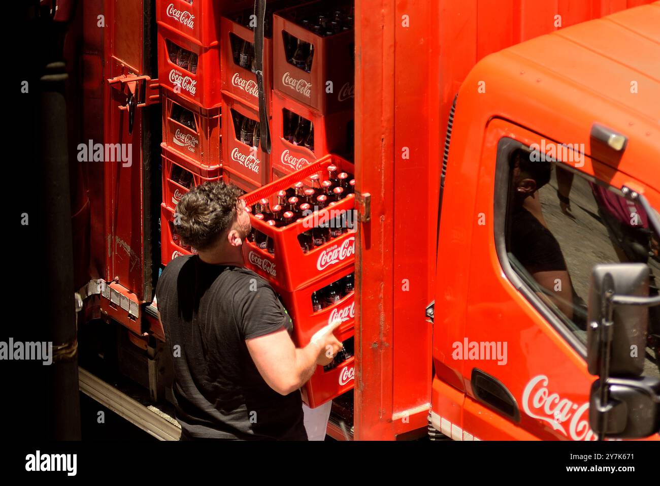 Coca-Cola delivery man taking bottle crates in a street of San Lorenzo ...