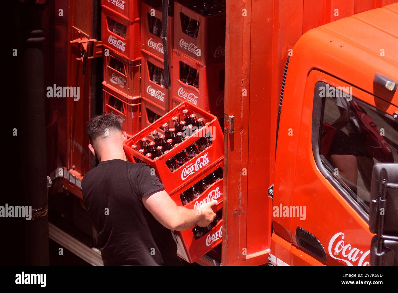 Coca-Cola delivery man taking bottle crates in a street of San Lorenzo ...