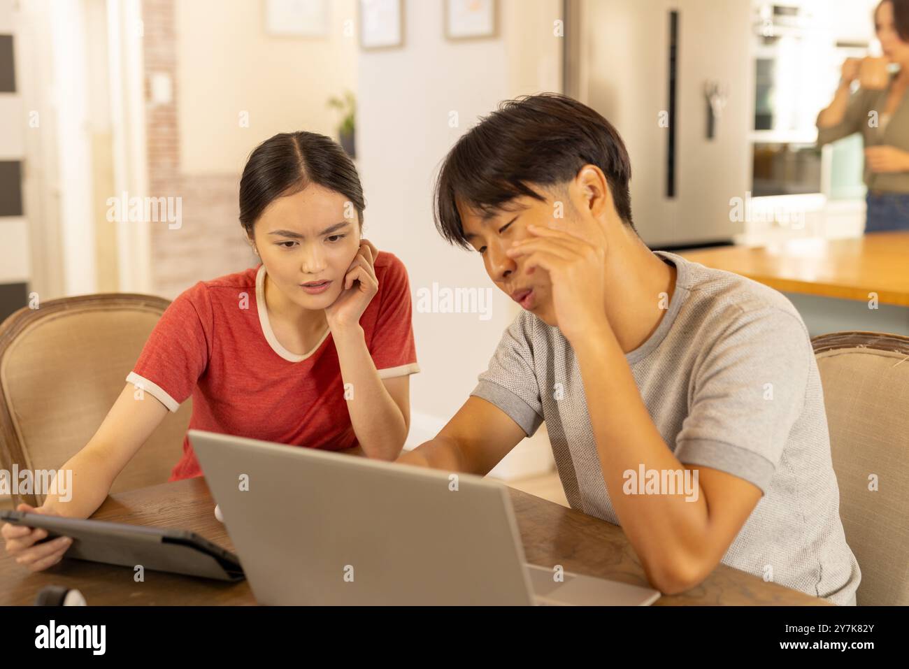 Using laptop and tablet, young asian brother and sister working ...