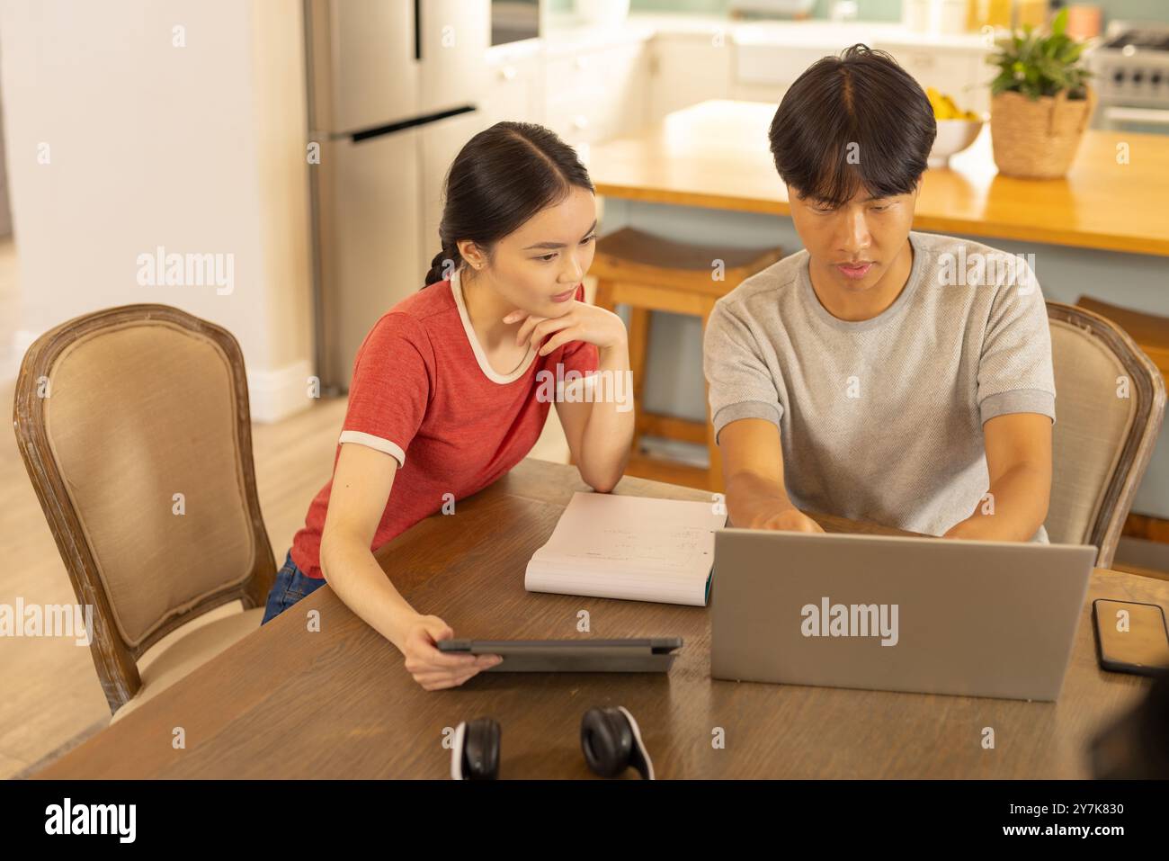 Working from home, asian brother and sister using laptop and tablet at kitchen table Stock Photo ...