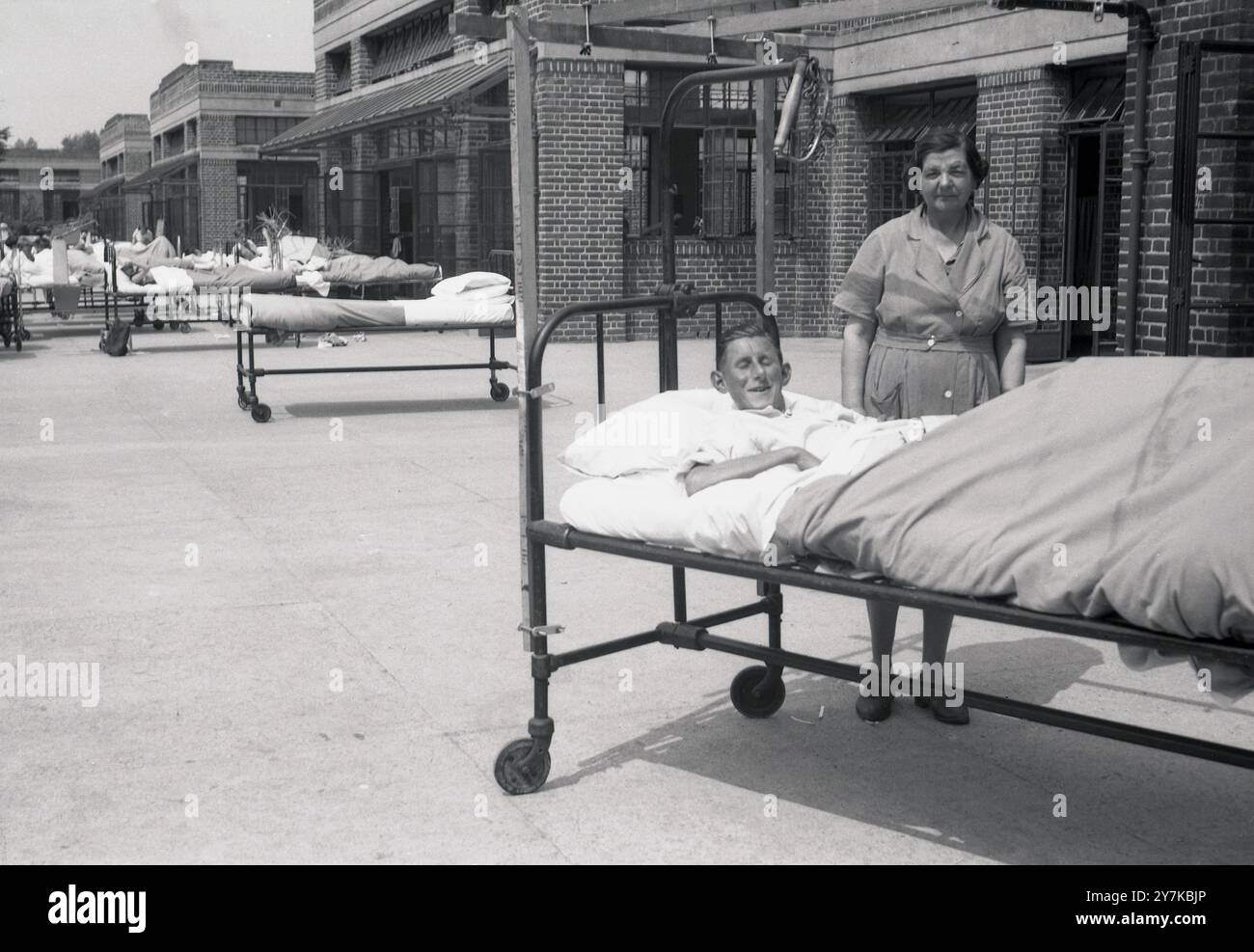 1936, historical, female helper standing beside male patient lying in ...