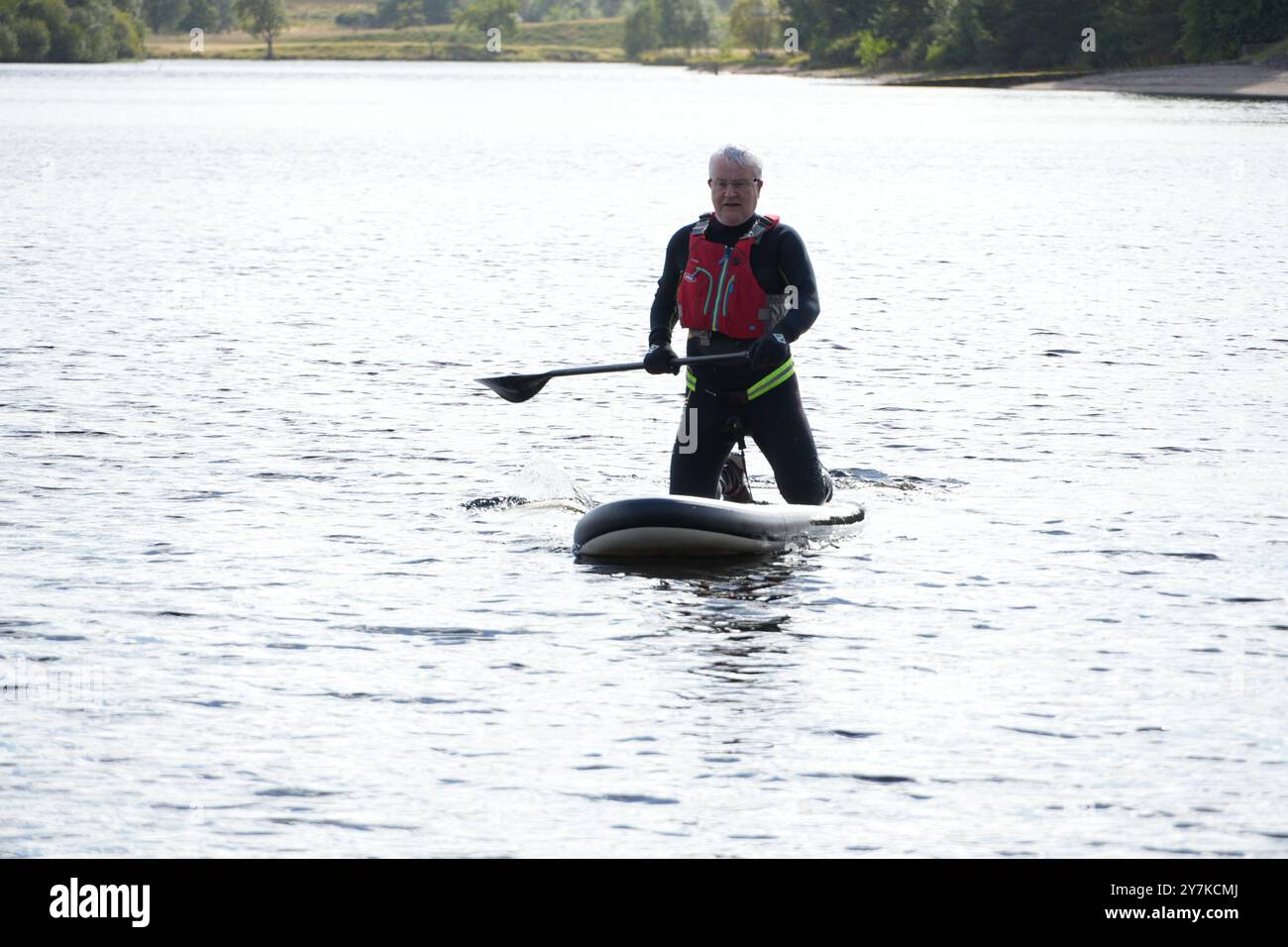 Man learning to paddle board (SUPB) on Loch Rannoch in Scotland, United ...