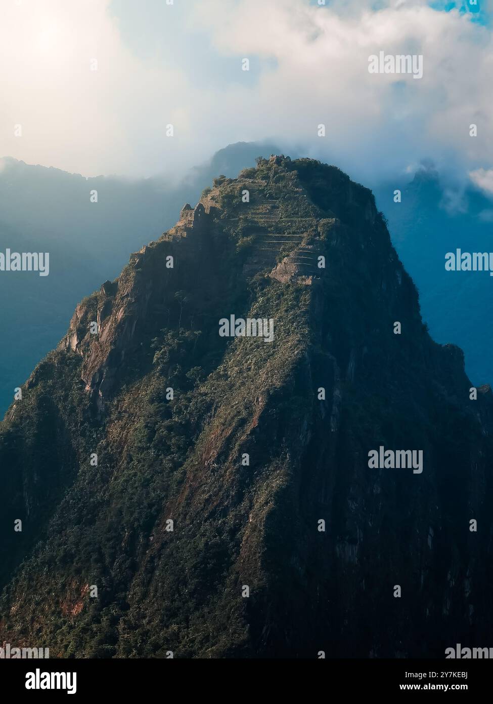 A majestic view of Huayna Picchu mountain with clouds surrounding it in ...