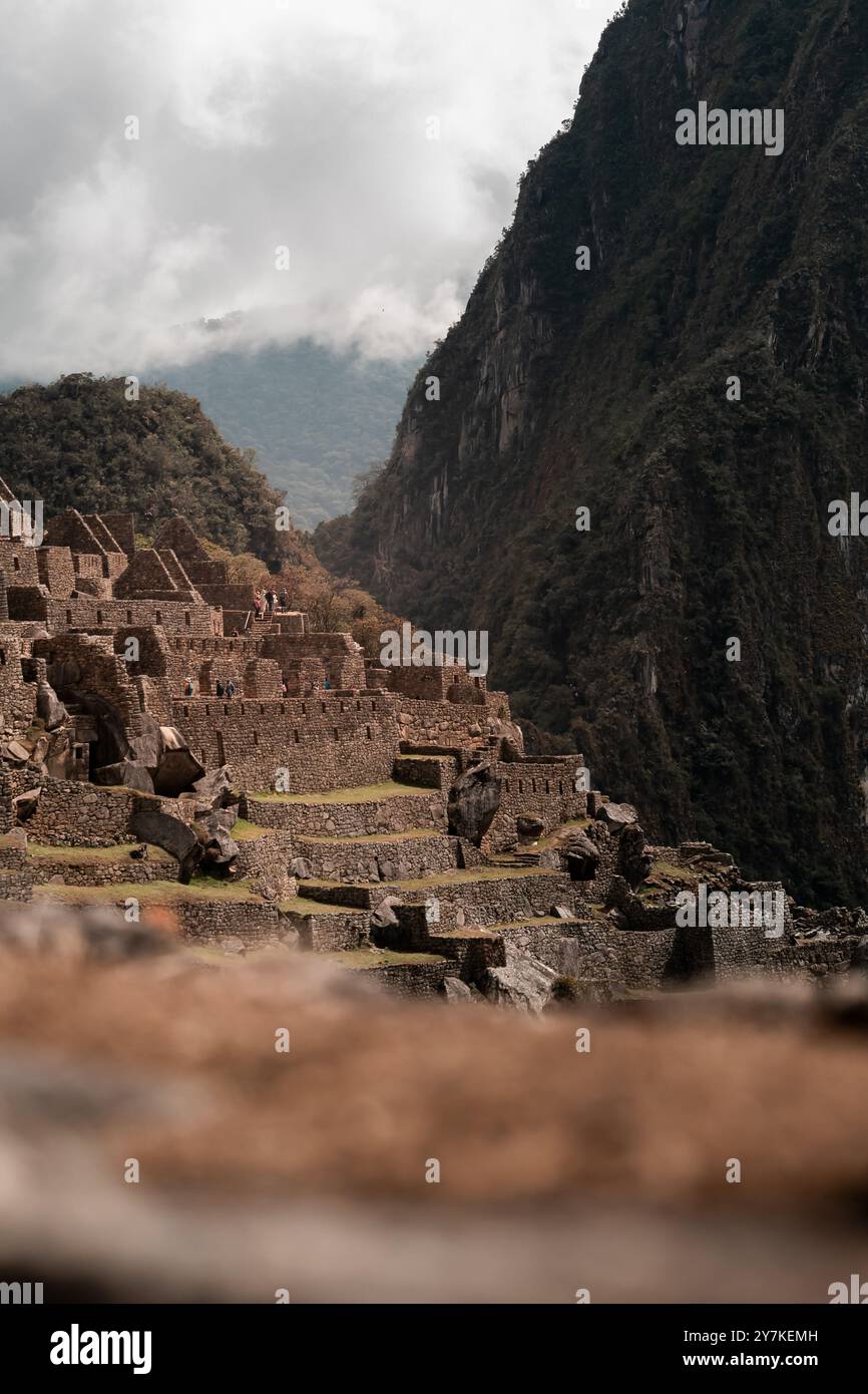 Machu Picchu ruins with a dramatic mountain backdrop and cloudy sky in ...
