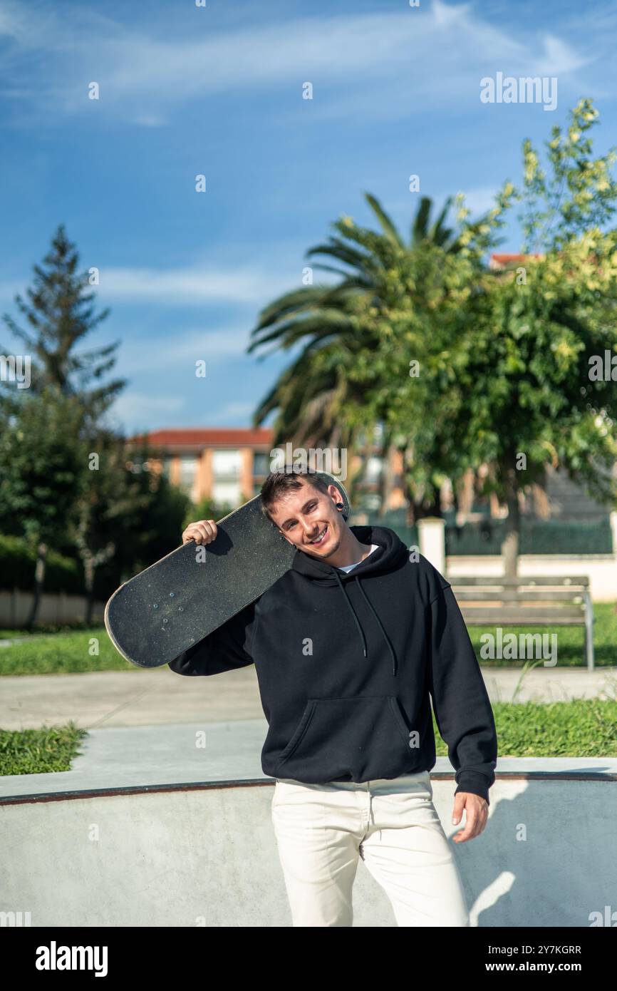vertical happy skater striking a pose while holding their skateboard ...