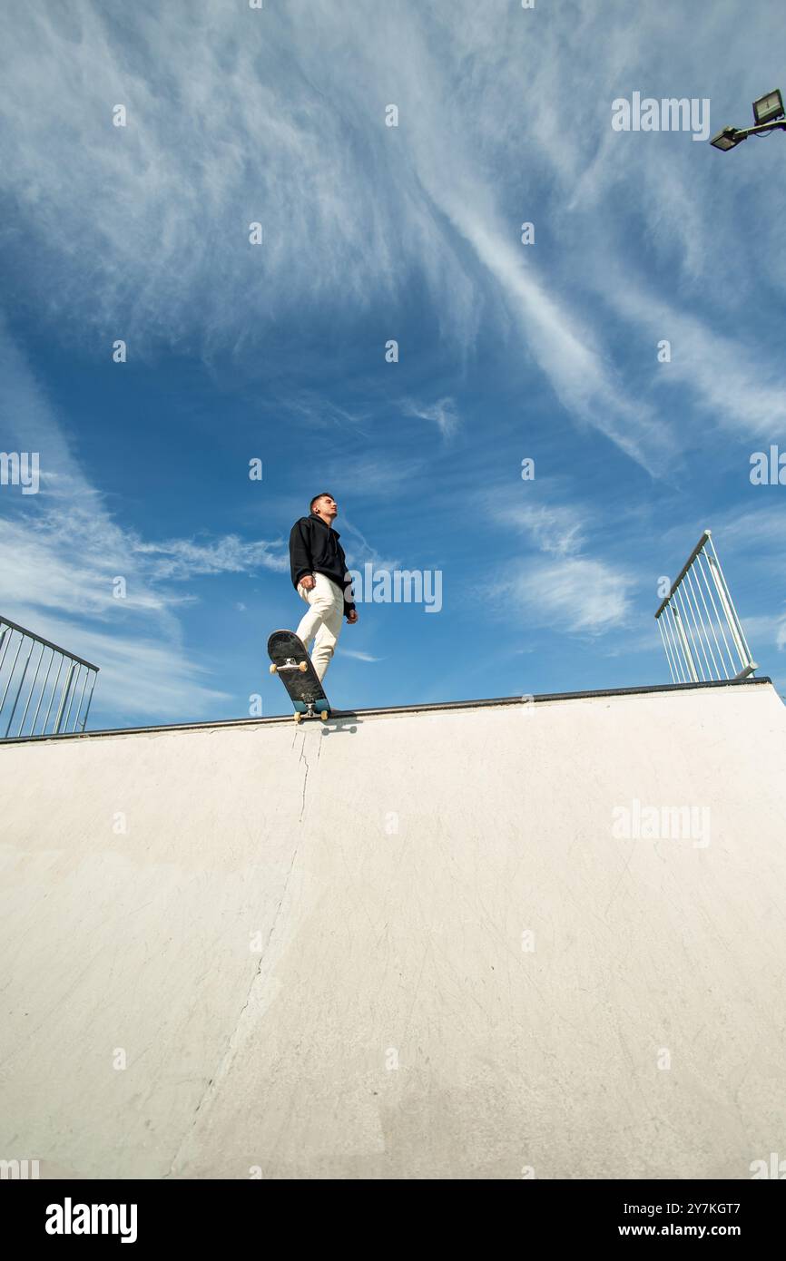 vertical skater standing on their board in skate park, looking up at ...