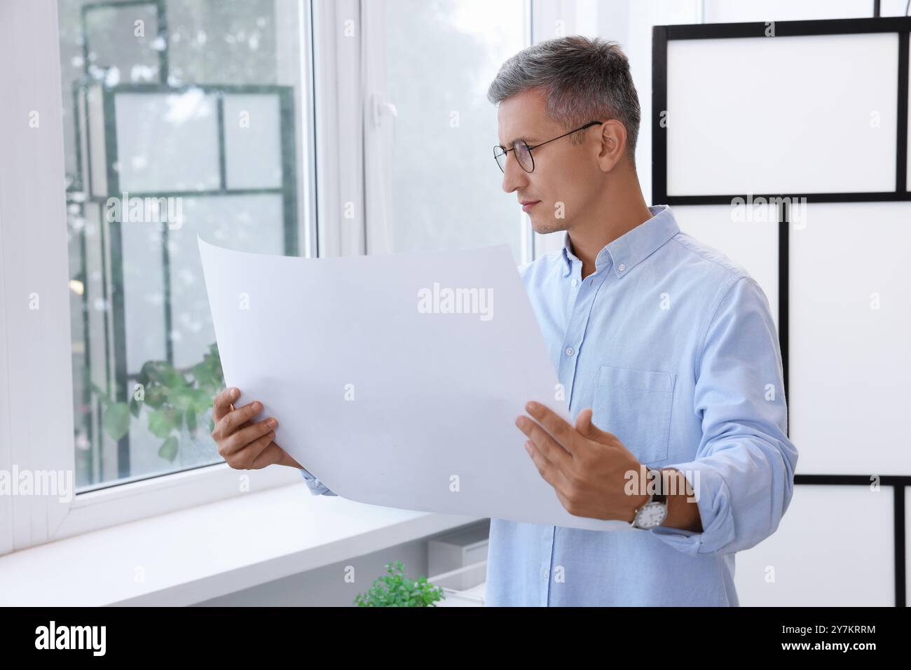 Architect holding paper sheet with engineering drawing in office Stock ...