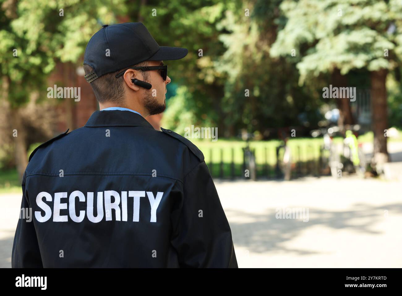Security guard in uniform and sunglasses outdoors, back view. Space for ...