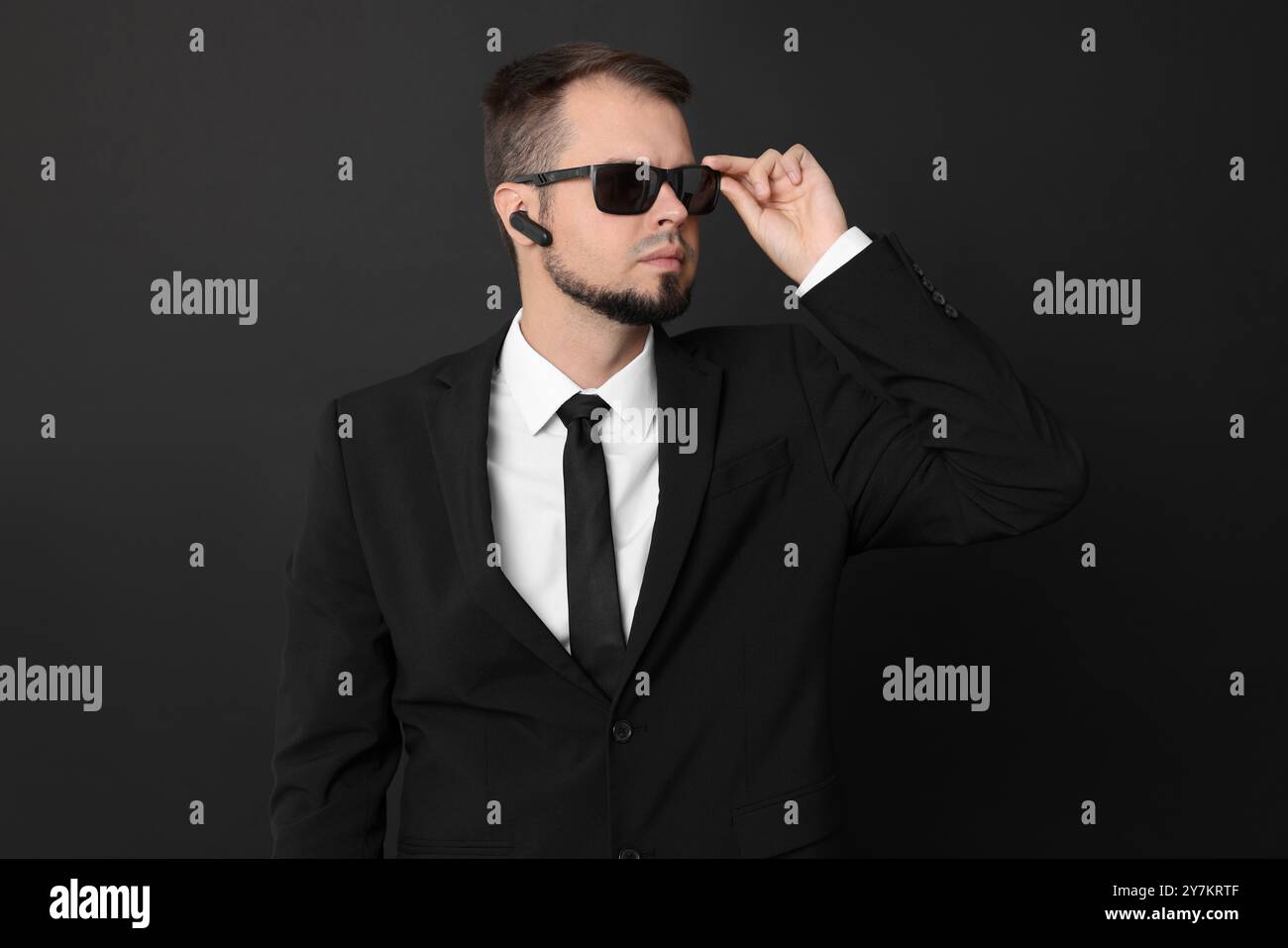 Young bodyguard in suit with sunglasses on black background Stock Photo ...