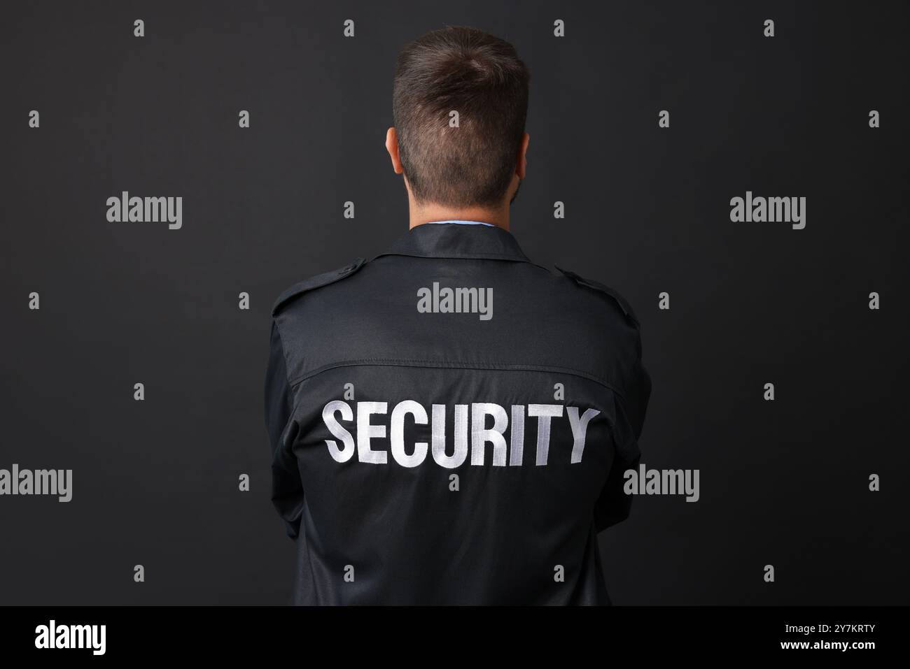 Security guard in uniform on black background, back view Stock Photo ...