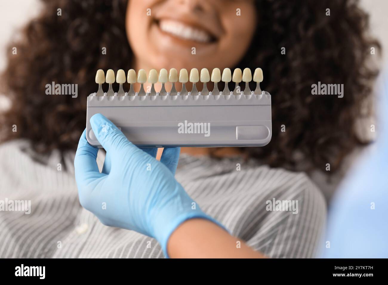Doctor checking young woman's teeth color in clinic, closeup. Dental ...