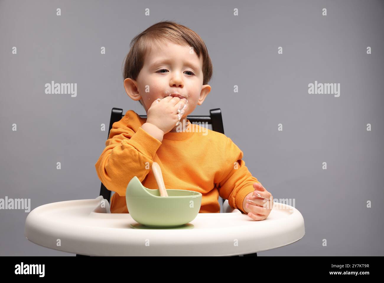 Cute little kid eating healthy baby food from bowl in high chair on ...